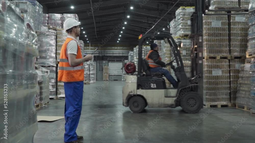 Logistics manager inspecting the worker offloading the pallets with ...