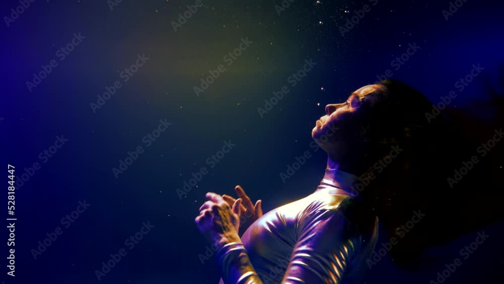 enigmatic woman is floating in mysterious dark depth and stretching ...