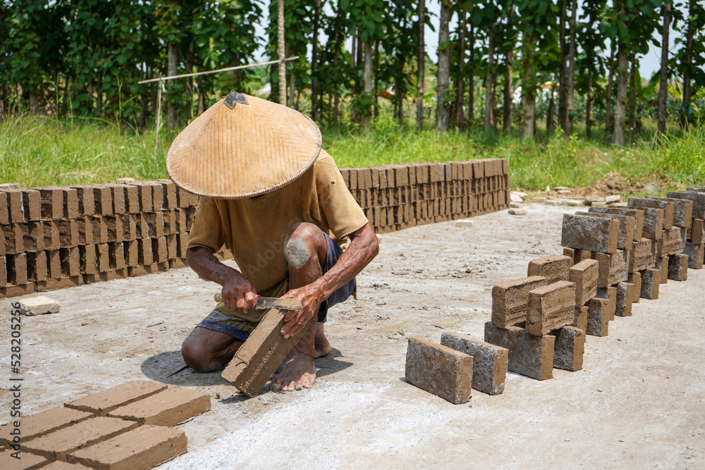 Kudus, Indonesia - September, 2022 : A male worker is making red bricks ...