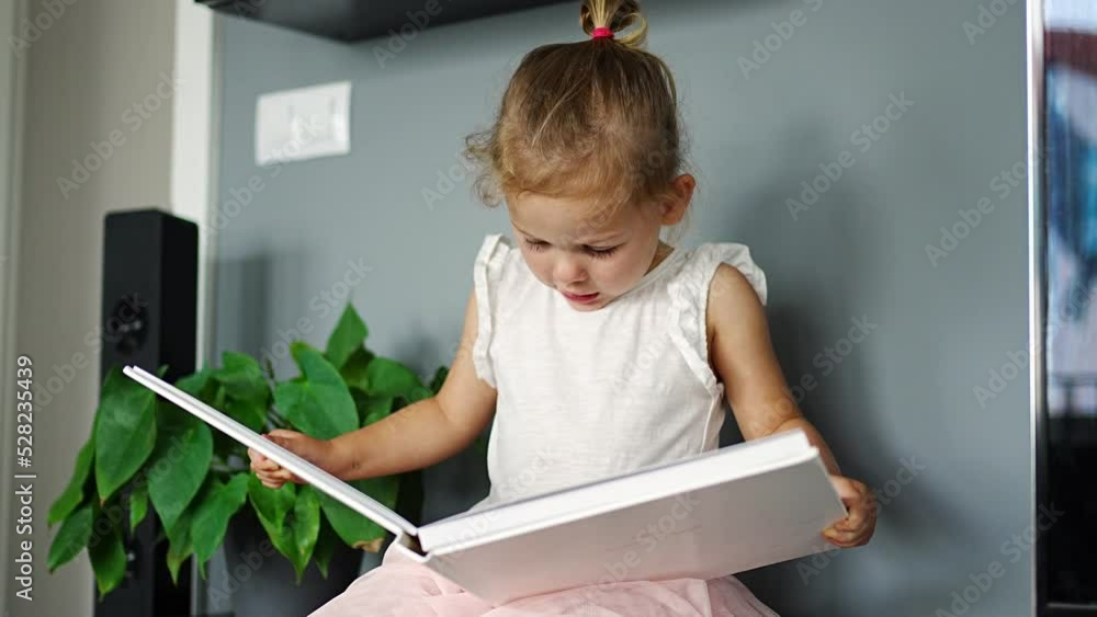 Happy cute little girl looking at photos in album. Happy smiling ...