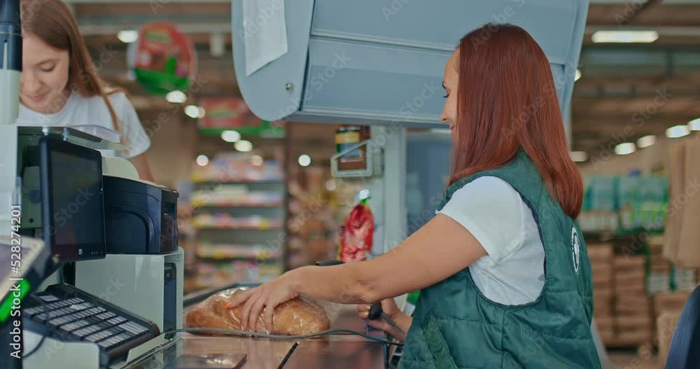 Female cashier punches the goods at the checkout, runs a barcode ...