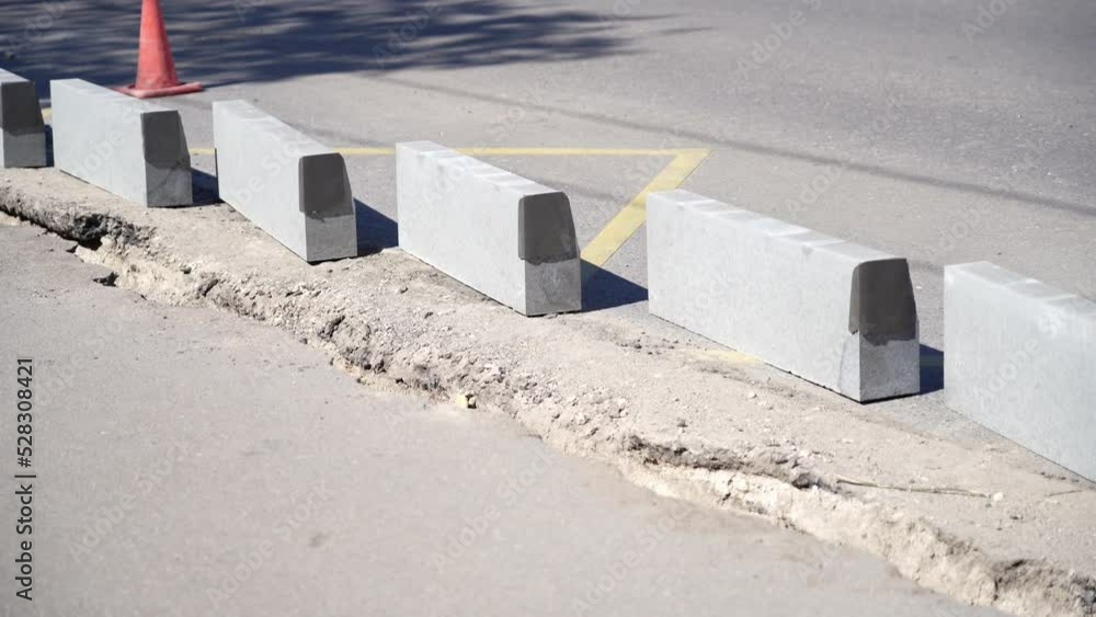 Roadside concrete curb stone with potholed road surface. Road repair ...