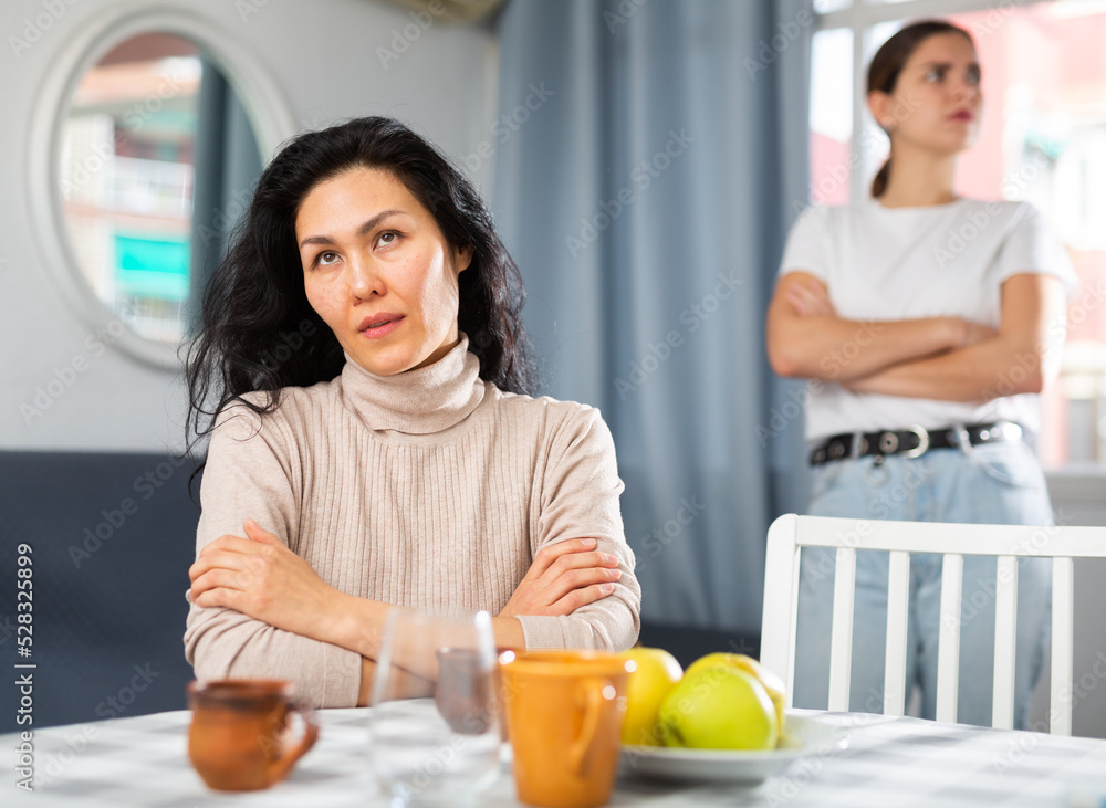 Upset disappointed woman sitting at home while girl calming her, asking ...
