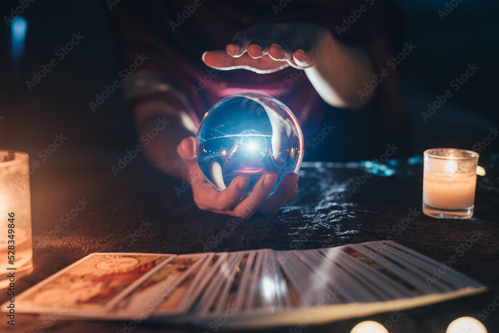 Fortune teller with illuminated crystal ball and tarot cards to ...