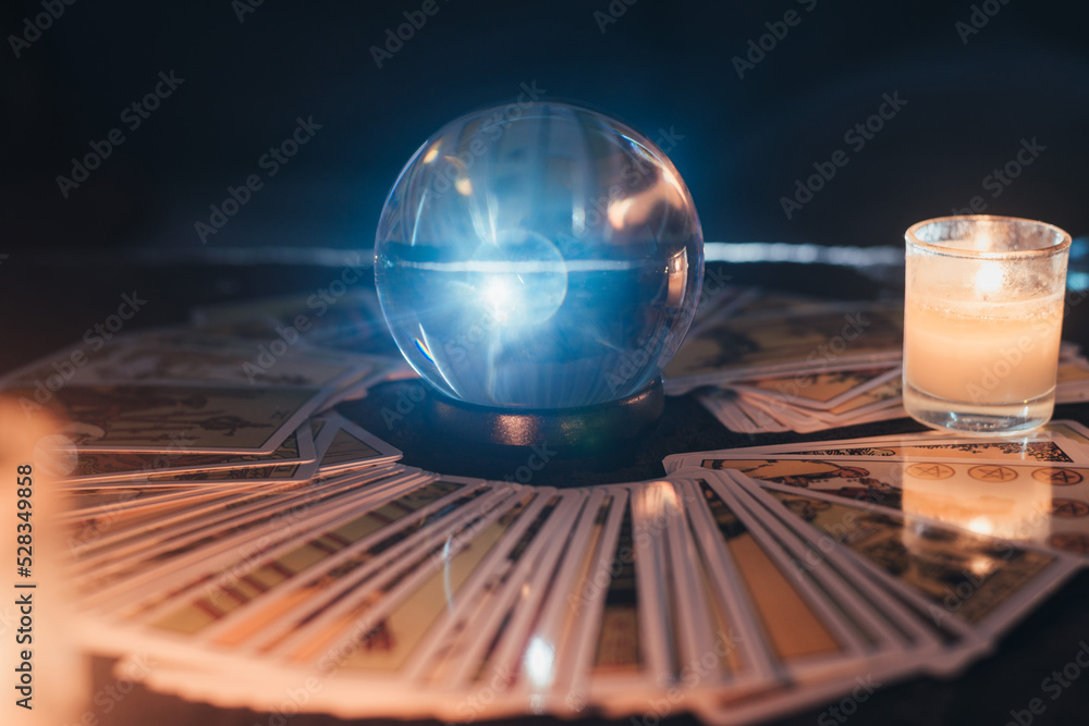 Fortune teller with illuminated crystal ball and tarot cards to ...