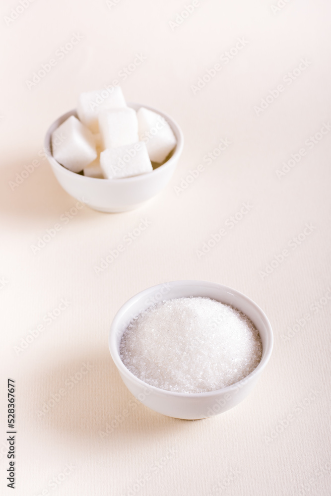 Granulated sugar and sugar cubes in bowls. Choosing between types of ...