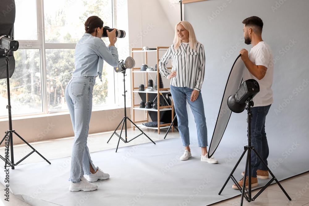 Female photographer and her assistant working with mature woman in ...