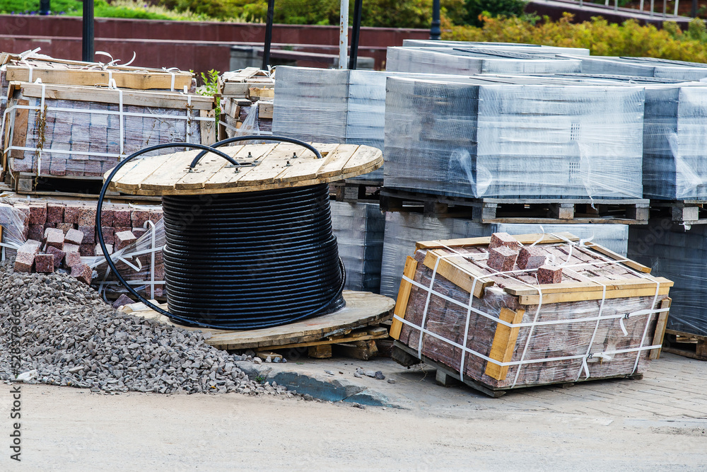 Large reel with electric cable and packing with paving stones on a ...