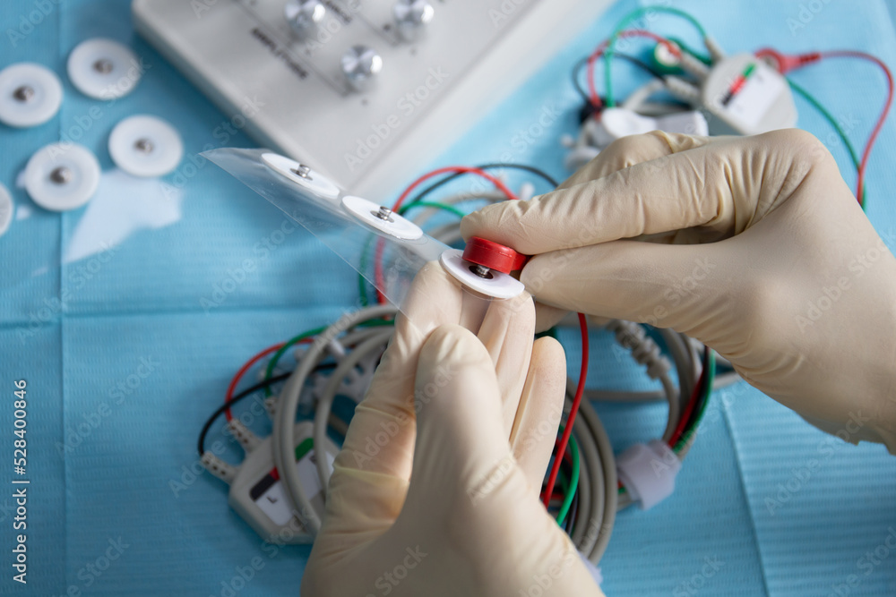 A close-up of the doctor's hands connect the electrodes for the ...