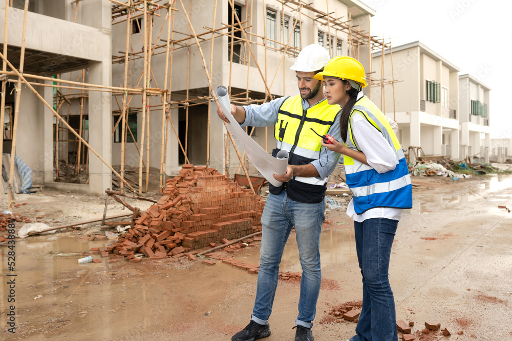 Engineer man and female architect wear safety helmets discuss housing ...