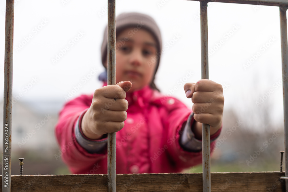 Little girl behind bars. Concept of homeless children. Child captivity ...