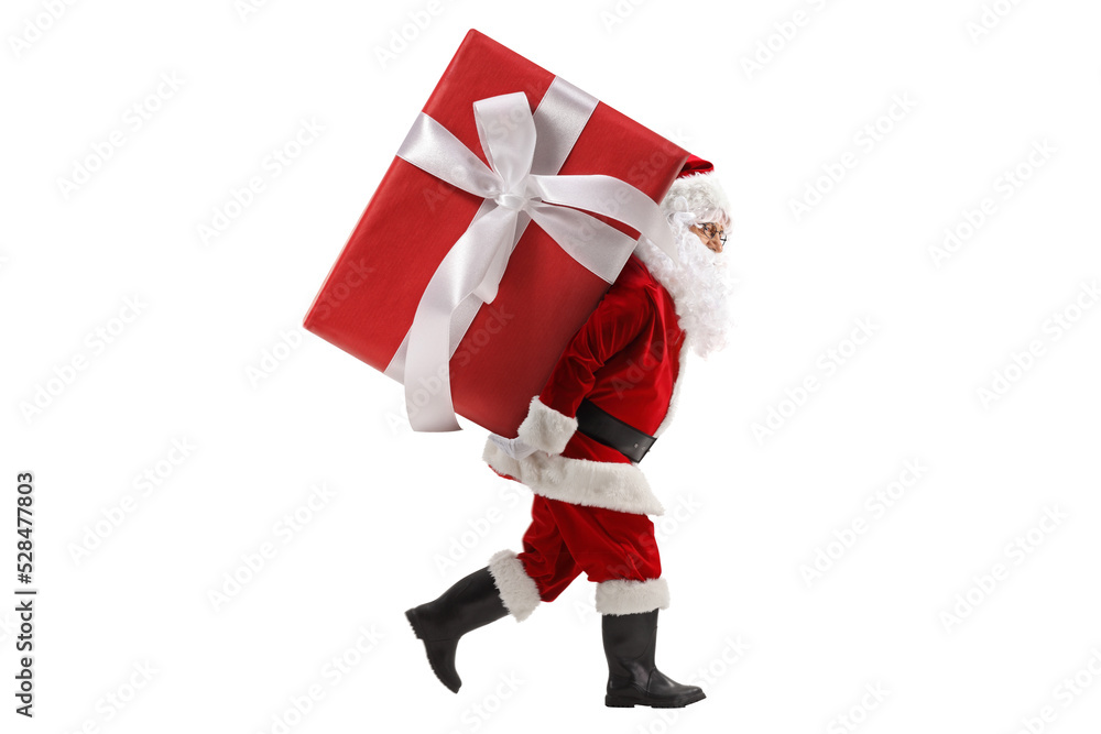 Full length profile shot of santa claus carrying a big preset on his ...