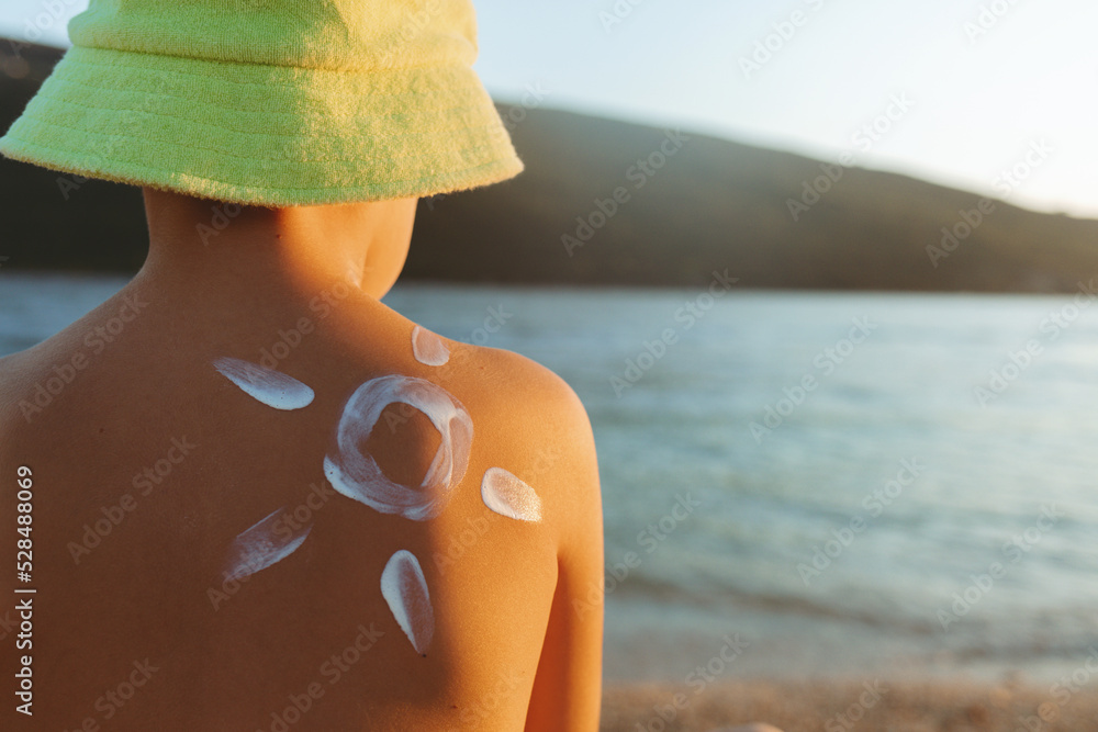 Cropped shot of a cute little boy posing with suntan lotion on his ...