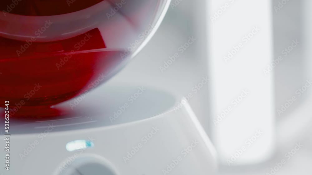 Bright laboratory. Round glass flask. Red liquid boils in the flask ...