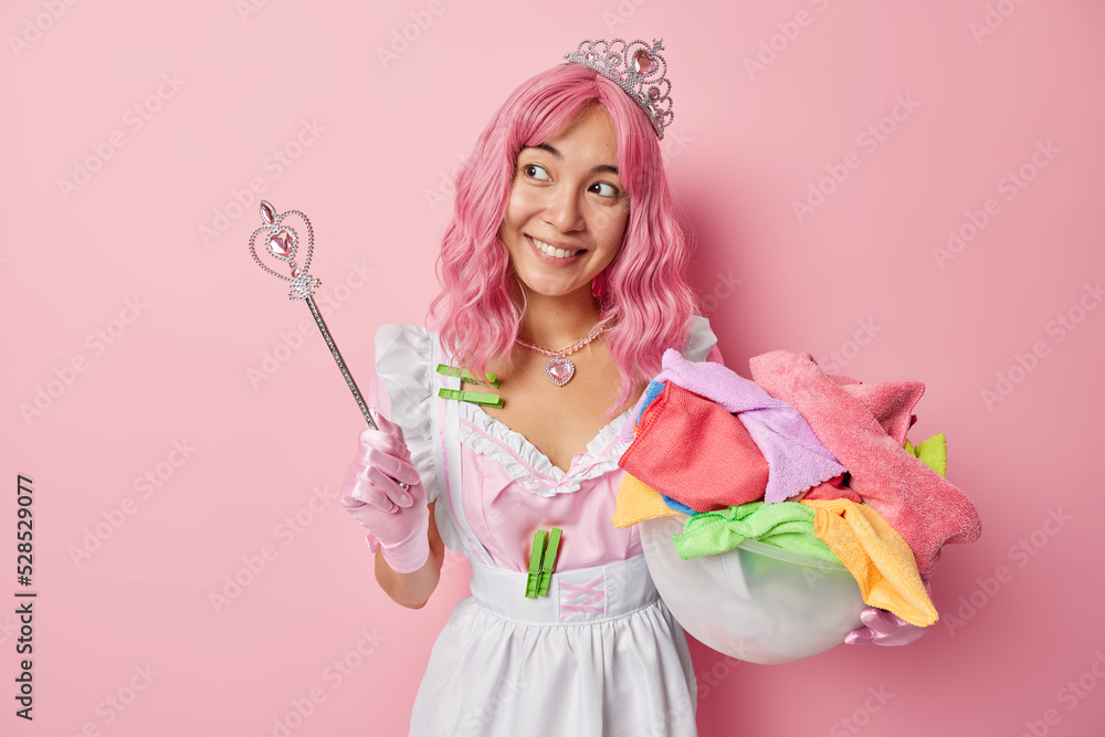 Beautiful thoughtful housemaid in white dress and crown on head holds ...