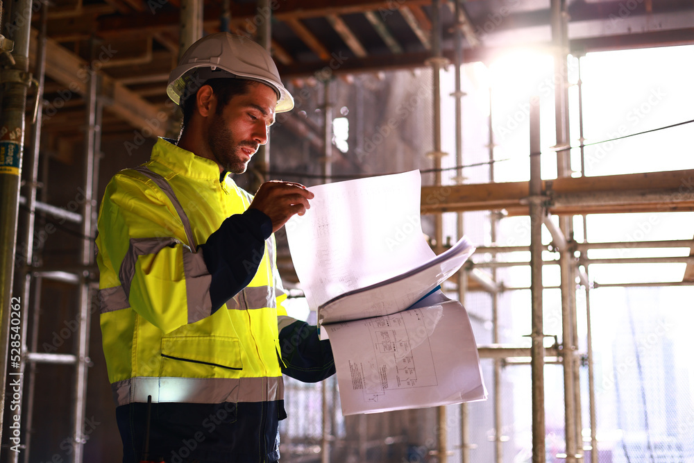 Handsome engineer with green safety jacket working at construction site ...