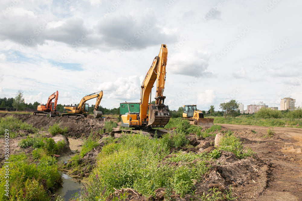 Three crawler excavators dig the earth with a bucket, and a bulldozer ...