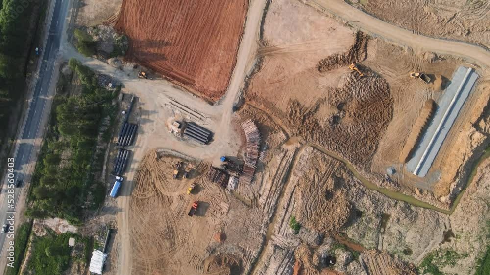 A wide construction site with industrial machinery and large piles of ...