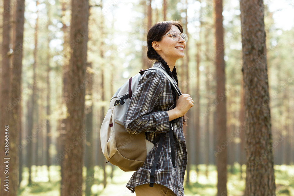 Young girl with backpack enjoying her hiking in the forest in summer ...
