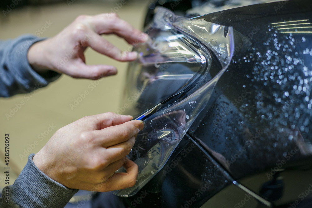 The process of installing PPF on the headlight of the car. PPF is a ...