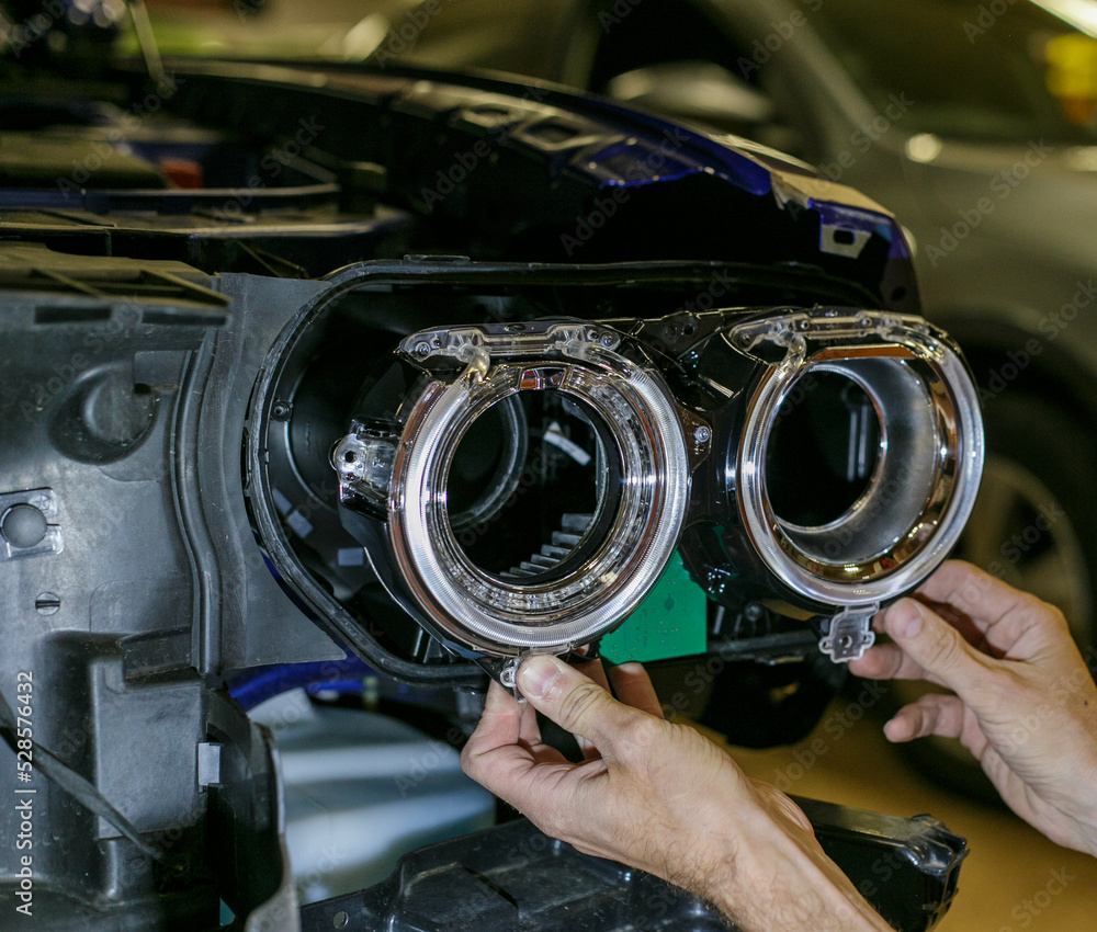 Car headlight in repair close-up. The car mechanic installs the lens in ...