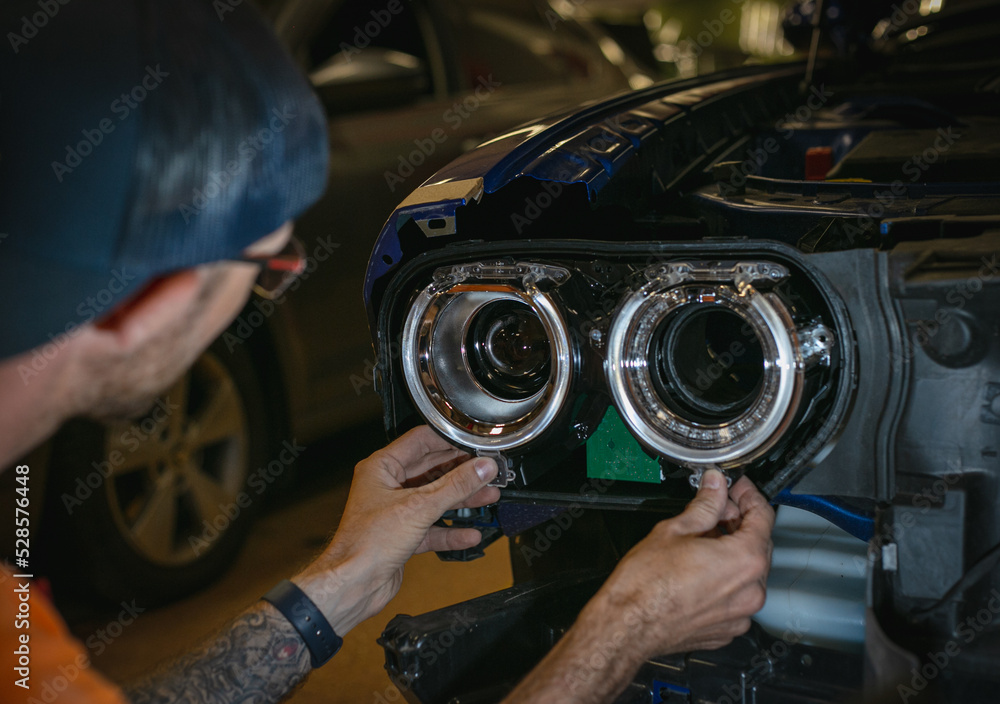 Car headlight in repair close-up. The car mechanic installs the lens in ...