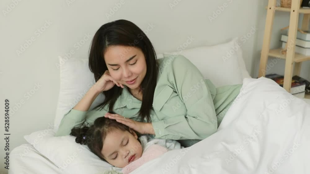 Asian mother caring for her daughter to lull sleep on the bed this ...