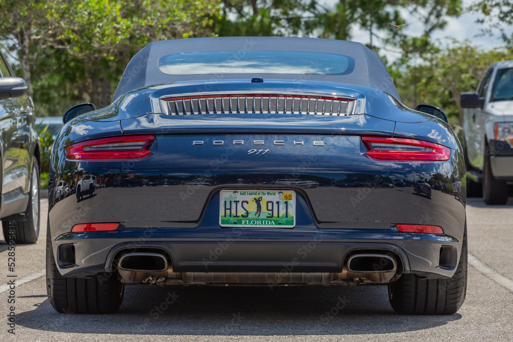 Rear End of a Convertible Porsche 911 in a Parking Lot with a Golfer on ...