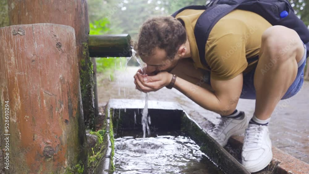Man drinking water from mountain spring. The man drinking the natural ...