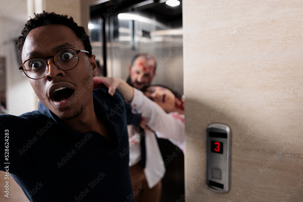 Frightened man running from evil zombies, trying to escape elevator ...