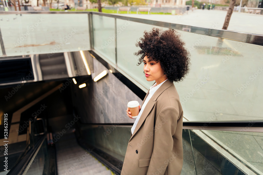 latin business woman entering the subway station on the escalator with ...
