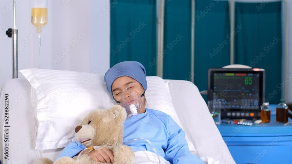 A little Indian girl with an oxygen mask lying in a hospital bed ...