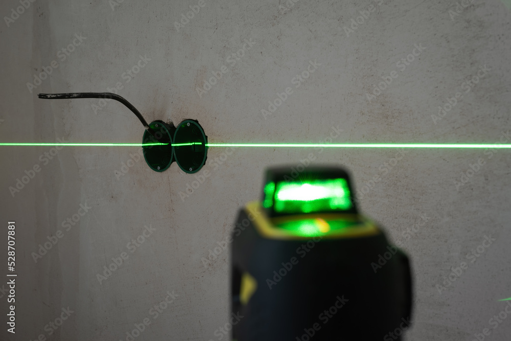 Electrical wiring work on the wall using laser level device. Plastic ...