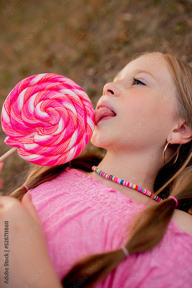 the child eats a bright lollipop. Beautiful girl model eats a bright ...