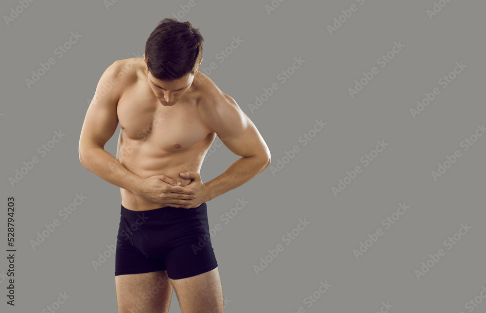 Young man touching left side of abdomen feeling severe pain standing on ...