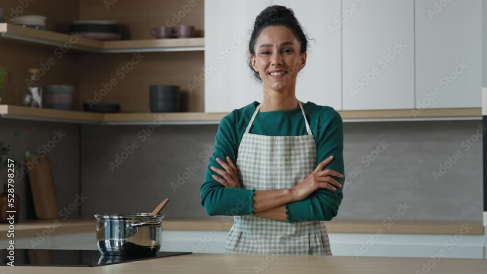 Cheerful beautiful woman wears apron standing in modern kitchen with ...