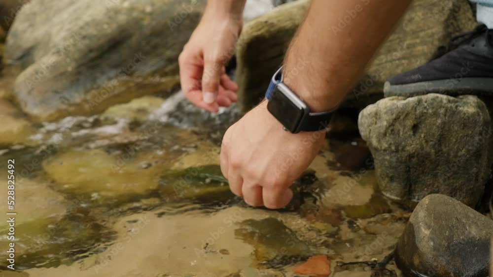 Man puts hands into clear water of stream washing stones Stock Video ...