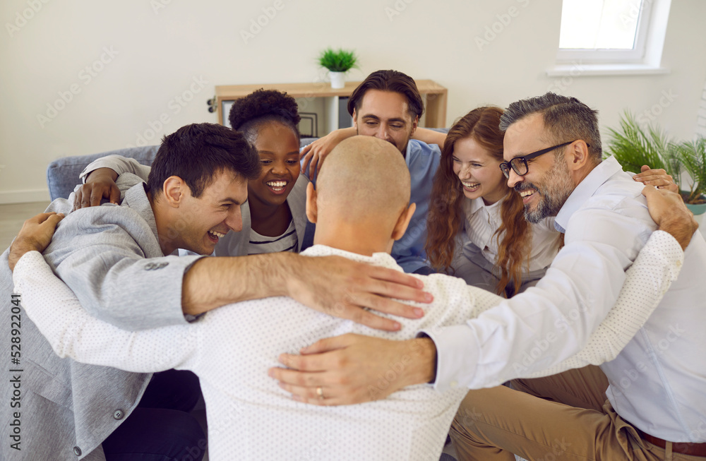 Team of successful positive colleagues laughing and hugging while ...