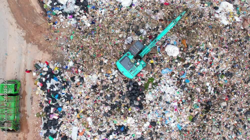 Drone flying over a huge pile of trash. workers sort out the garbage in ...