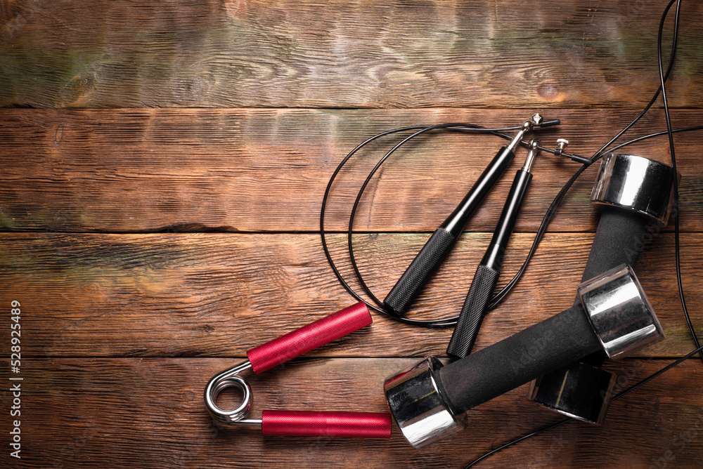 Small dumbbell, skipping rope and carpal expander on the wooden floor ...