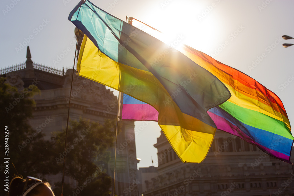 Ukrainian flag and rainbow LGBT flag against a sunny sunset sky. A ...