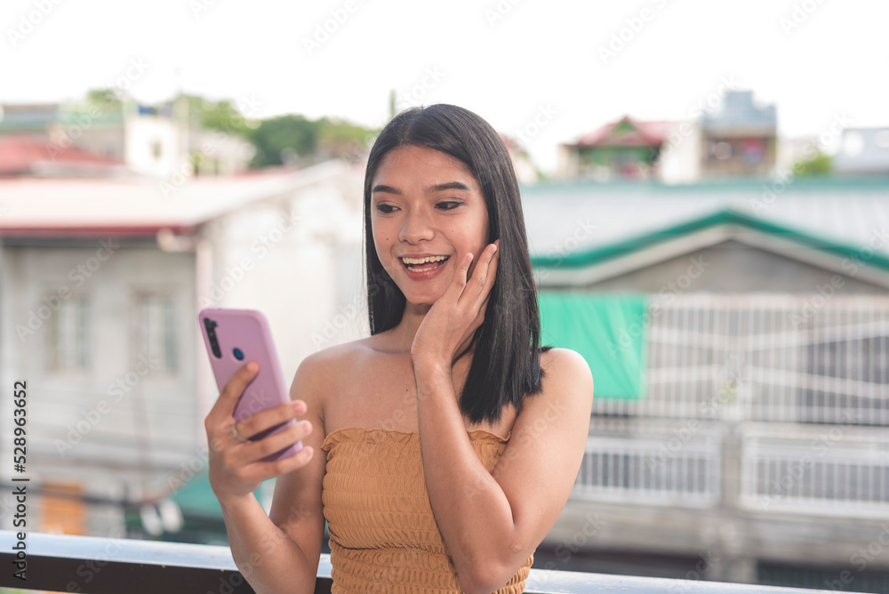A young Southeast Asian woman is video chatting with her overseas ...