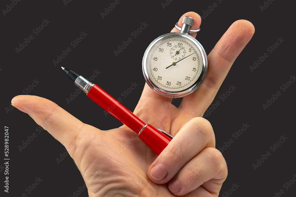 hand with a mechanical analog stopwatch on a dark background. Time part ...