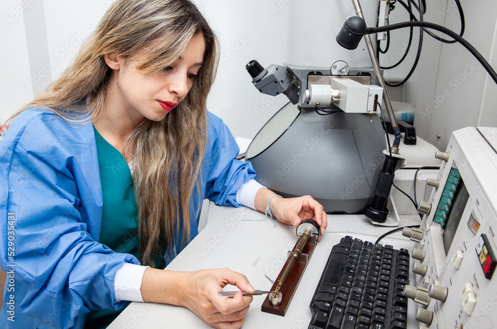Young female scientist loading a grid with an specimen on the sample ...
