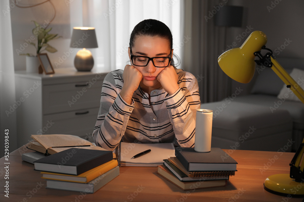 Tired young woman with energy drink studying at home Stock Photo ...