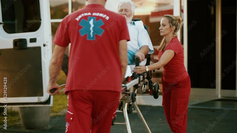 Sequence of shots of team of paramedics transporting old patient on ...