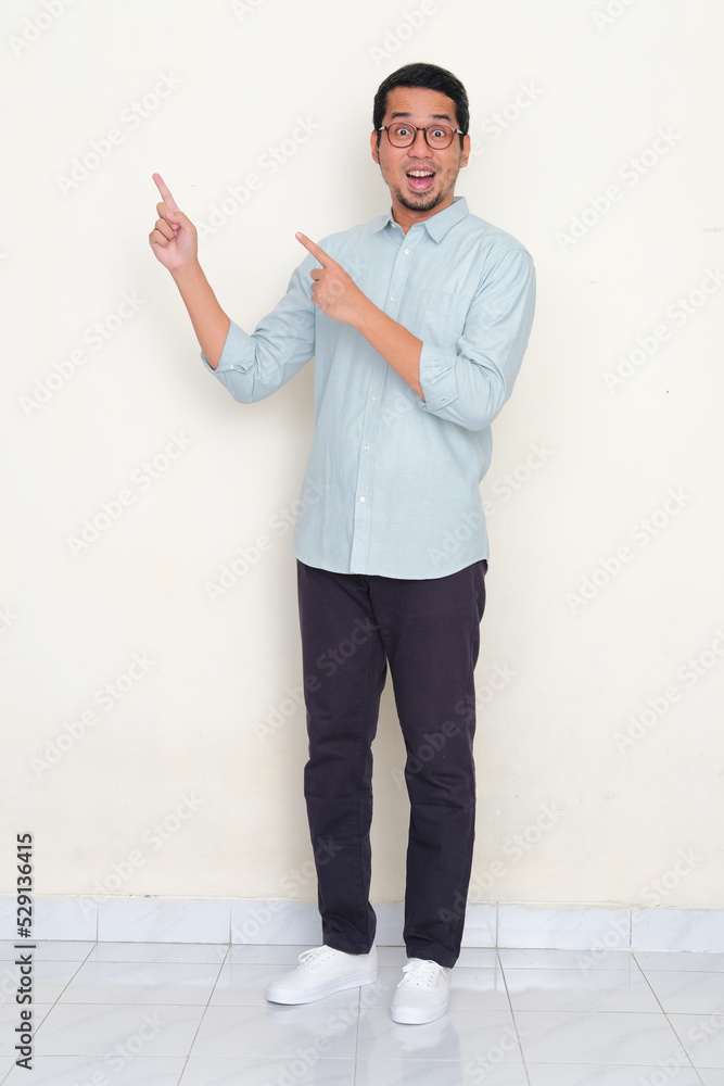 Full body portrait of Asian man pointing to the right side with excited ...