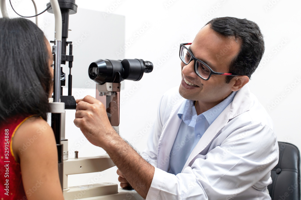 Indian girl and optometrist doing eye test with slit lamp in modern ...
