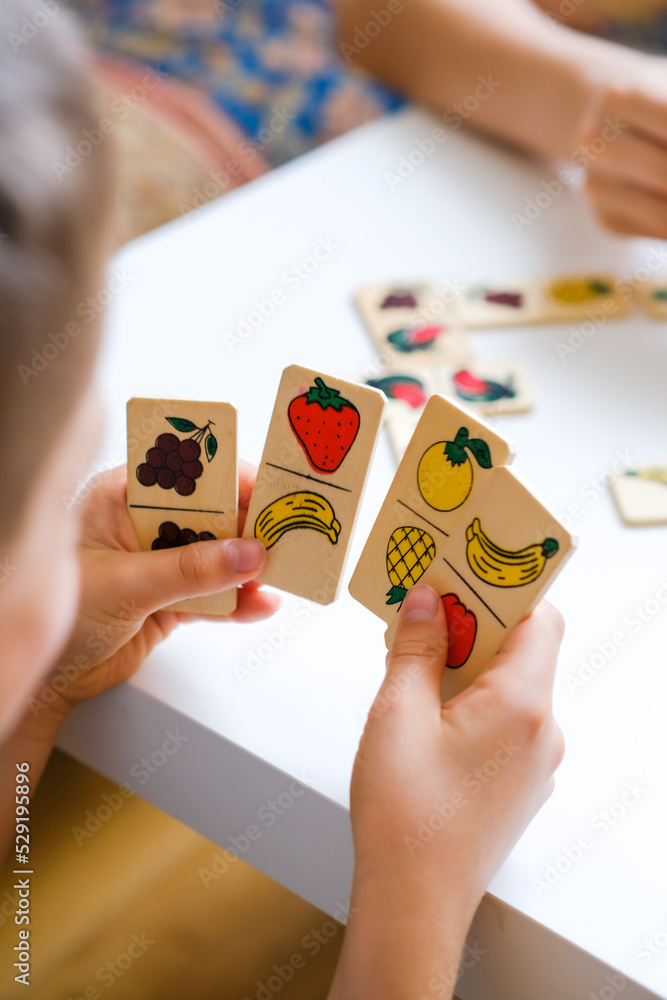 Two children are playing Bingo board Dominoes game. Cozy home. Joy and ...