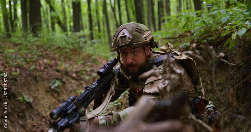 military sniper in combat pose walks with a rifle along an avrag in the ...